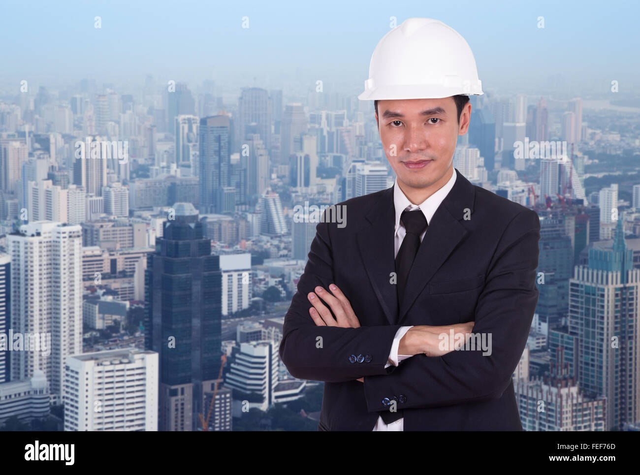 engineer in white helmet with arms crossed, city background Stock Photo ...