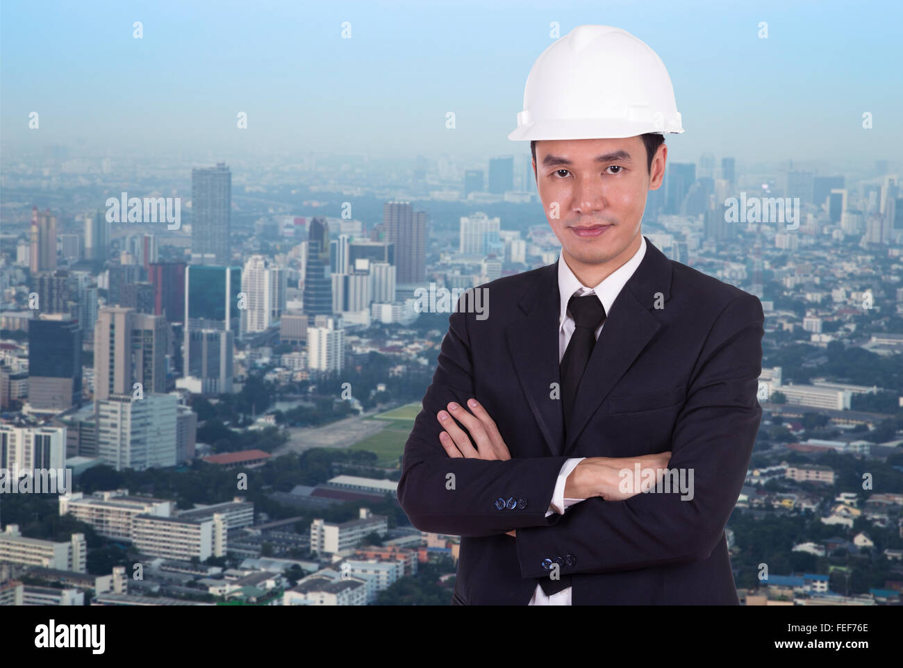 engineer in white helmet with arms crossed, city background Stock Photo ...