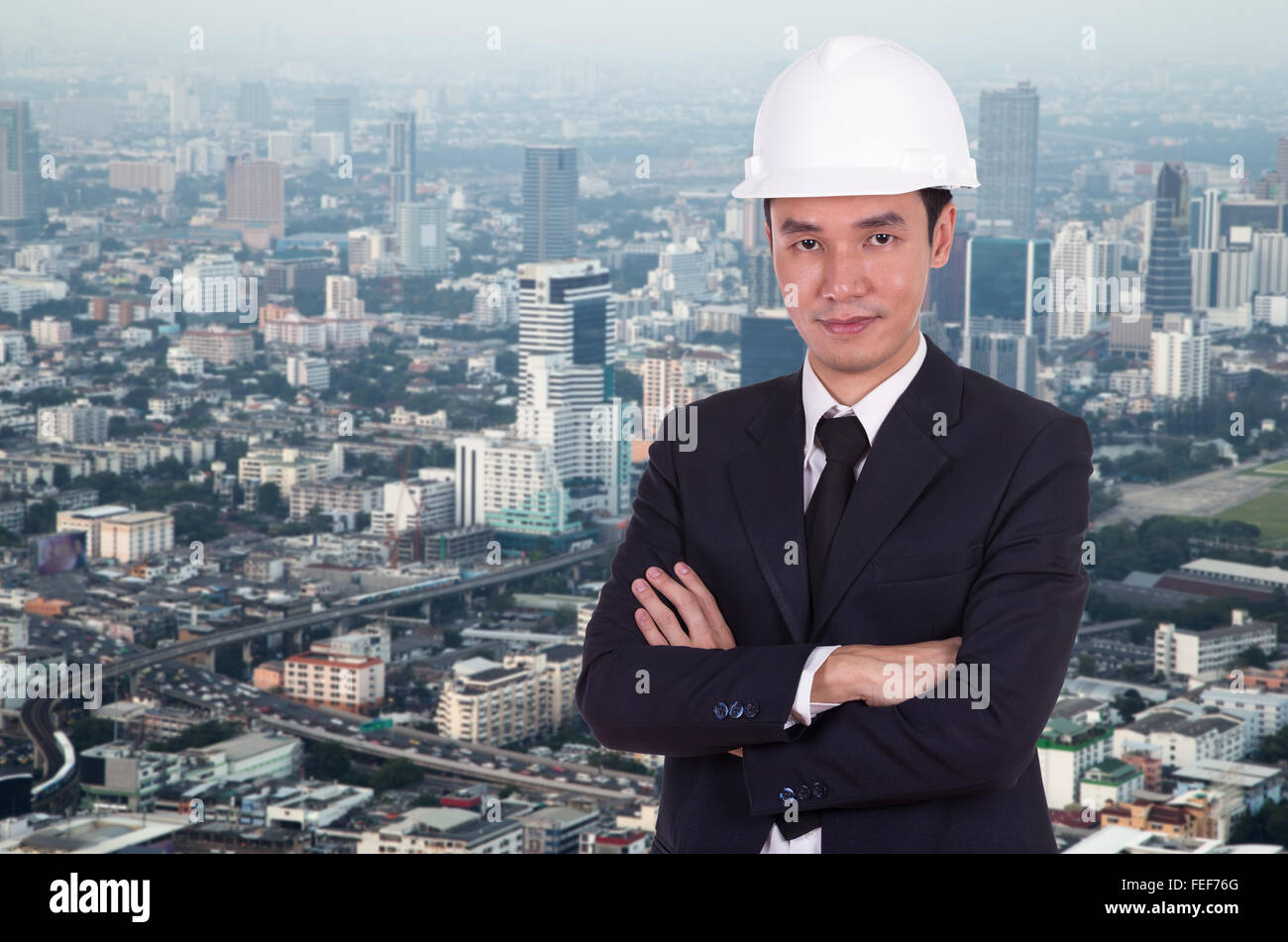 engineer in white helmet with arms crossed, city background Stock Photo ...