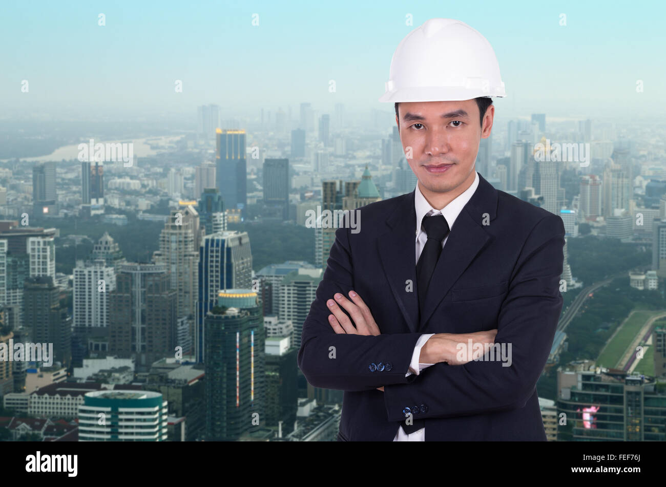 engineer in white helmet with arms crossed, city background Stock Photo ...