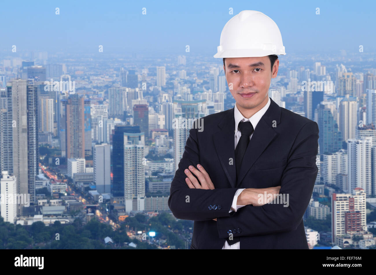 engineer in white helmet with arms crossed, city background Stock Photo ...