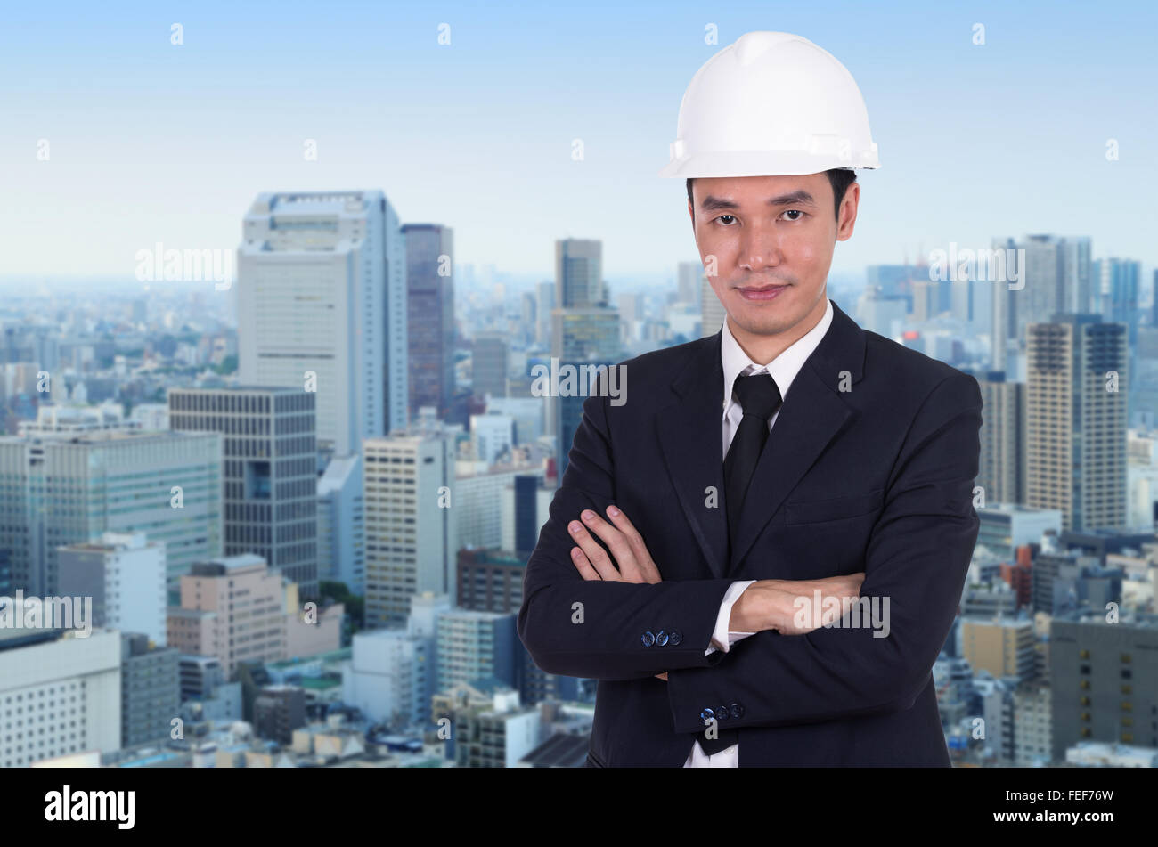 engineer in white helmet with arms crossed, city background Stock Photo ...