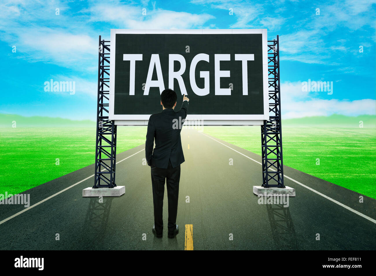 businessman standing on road and pointing with large sign of target ...