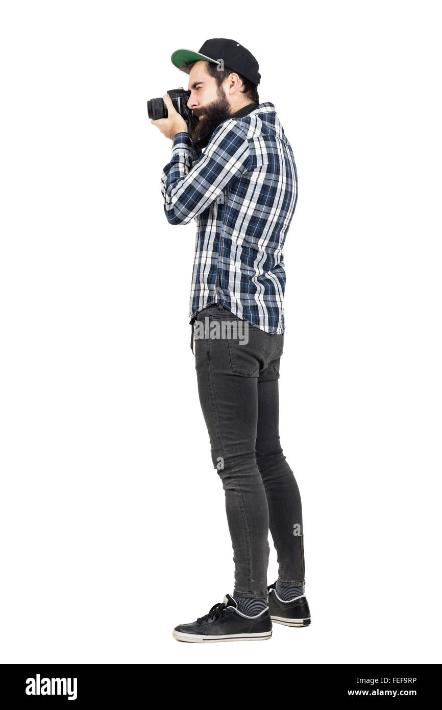 Side view of hipster wearing baseball cap taking photo with dslr camera ...