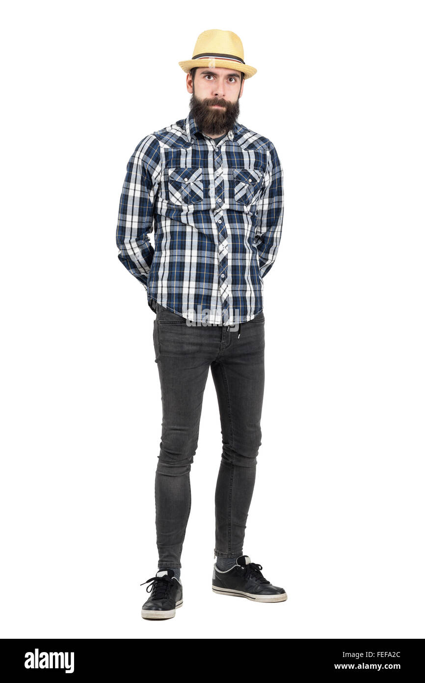 Serious hipster wearing straw hat with hands behind looking at camera ...