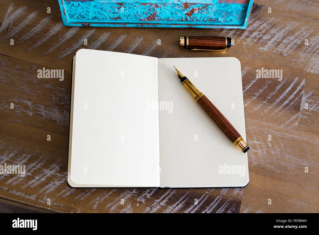 Classic fountain pen and open notebook on wooden table, with turquoise ...