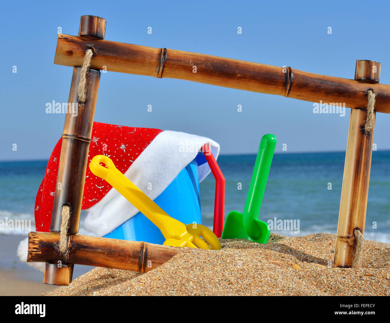 Children's toys and Santa's hat in bamboo frame on the beach against a ...