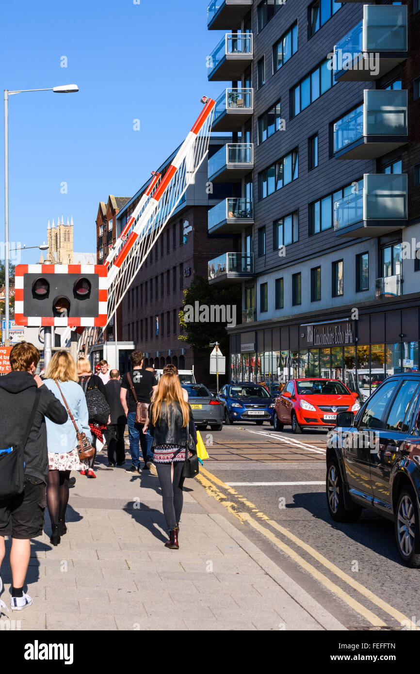 Railway level crossing barriers rising and people crossing the railway ...