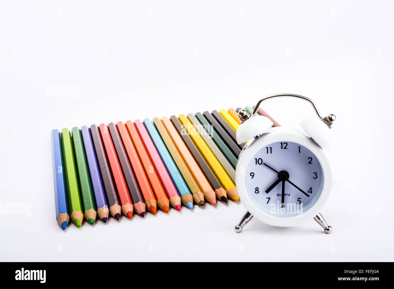 Colour pencil with alarm clock on a white background Stock Photo - Alamy