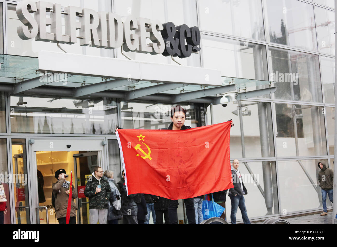 A young man stands holding a Communist party flag outside Selfridge's ...