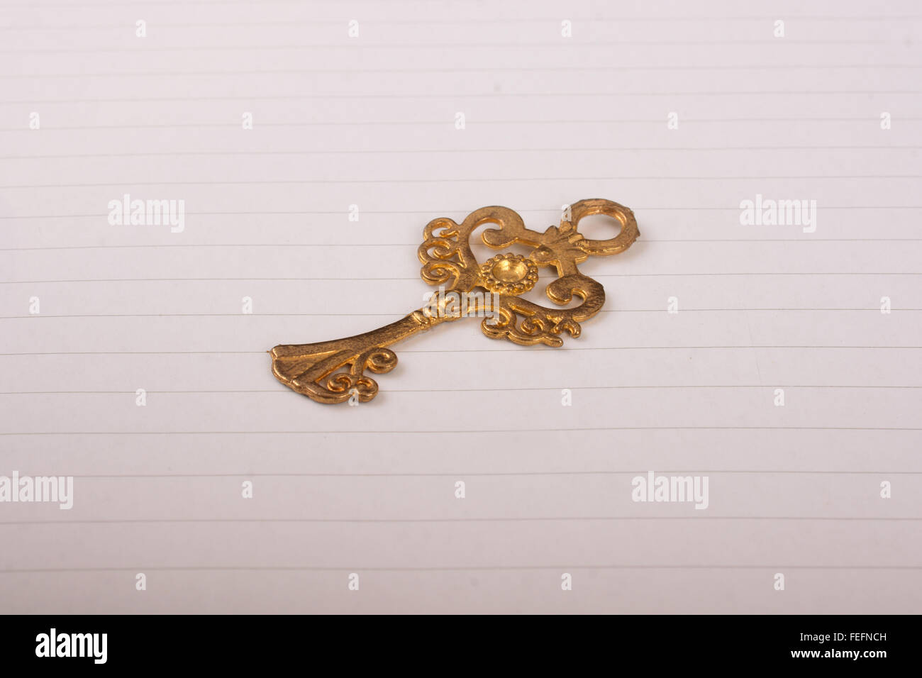 Golden color decorative key on lined sheet of paper Stock Photo - Alamy