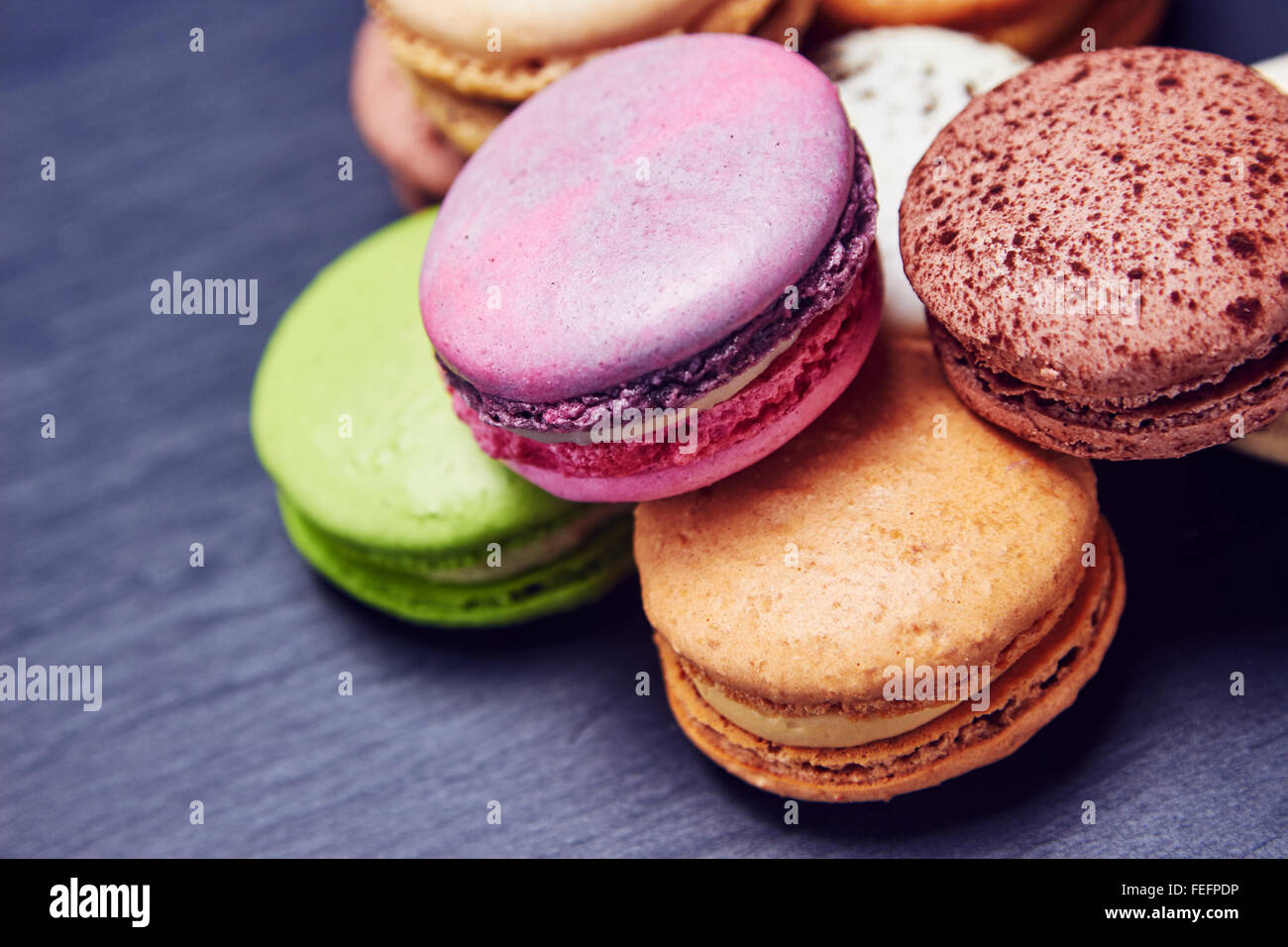 Different colors of macaroons sweets on a dark background Stock Photo ...