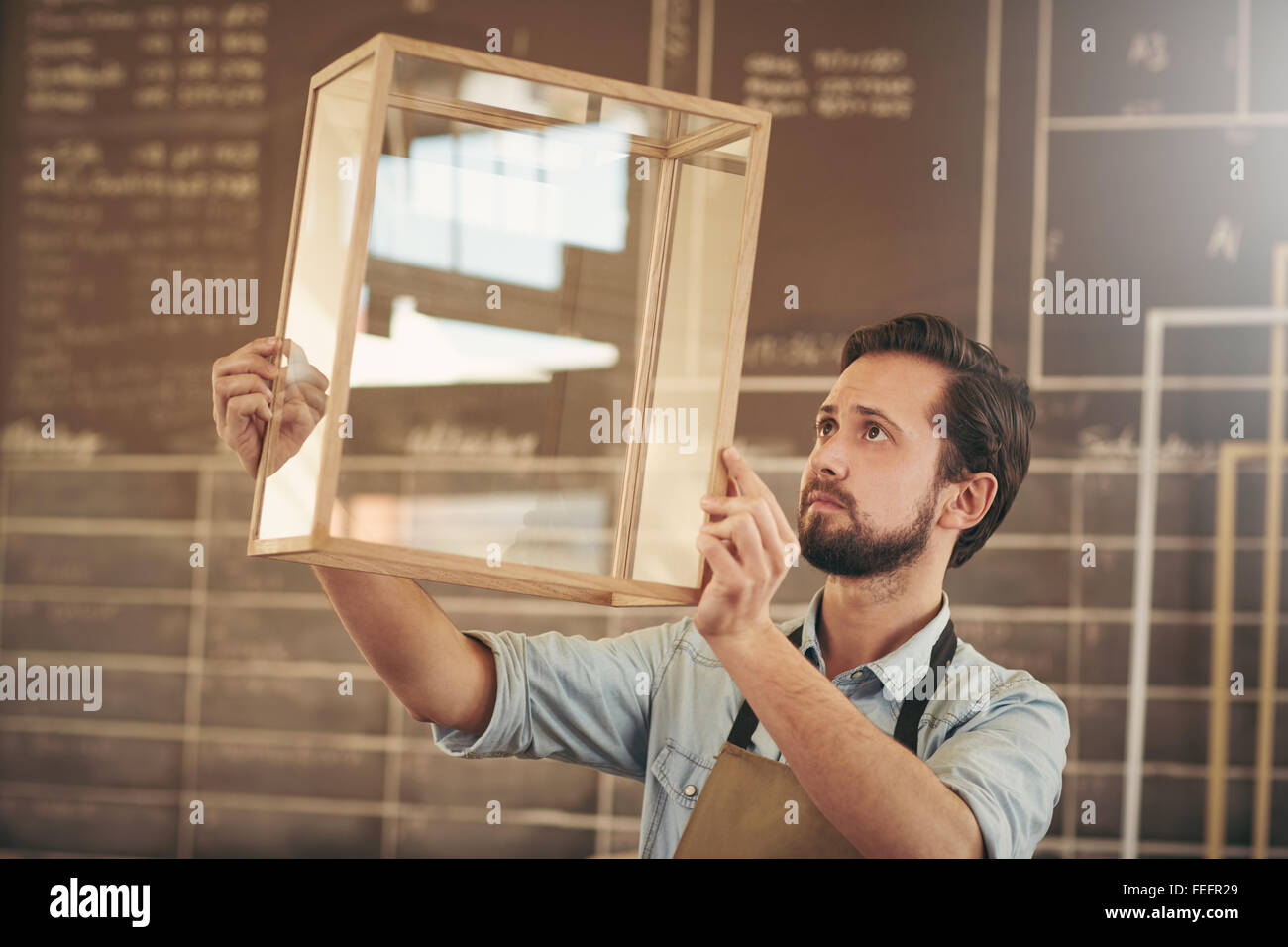 Designer looking carefully at a new product made from glass and wood in ...