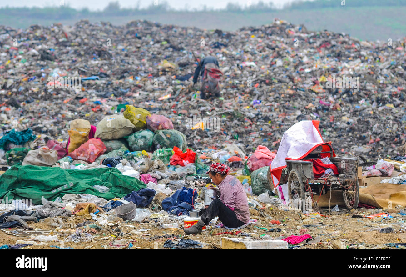 A woman is eating food in a garbage site in Xiangyang, Hubei province ...