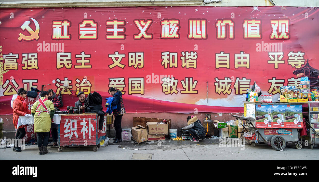 Chinese vendors work in front of a boad with propoganda of "China dream ...