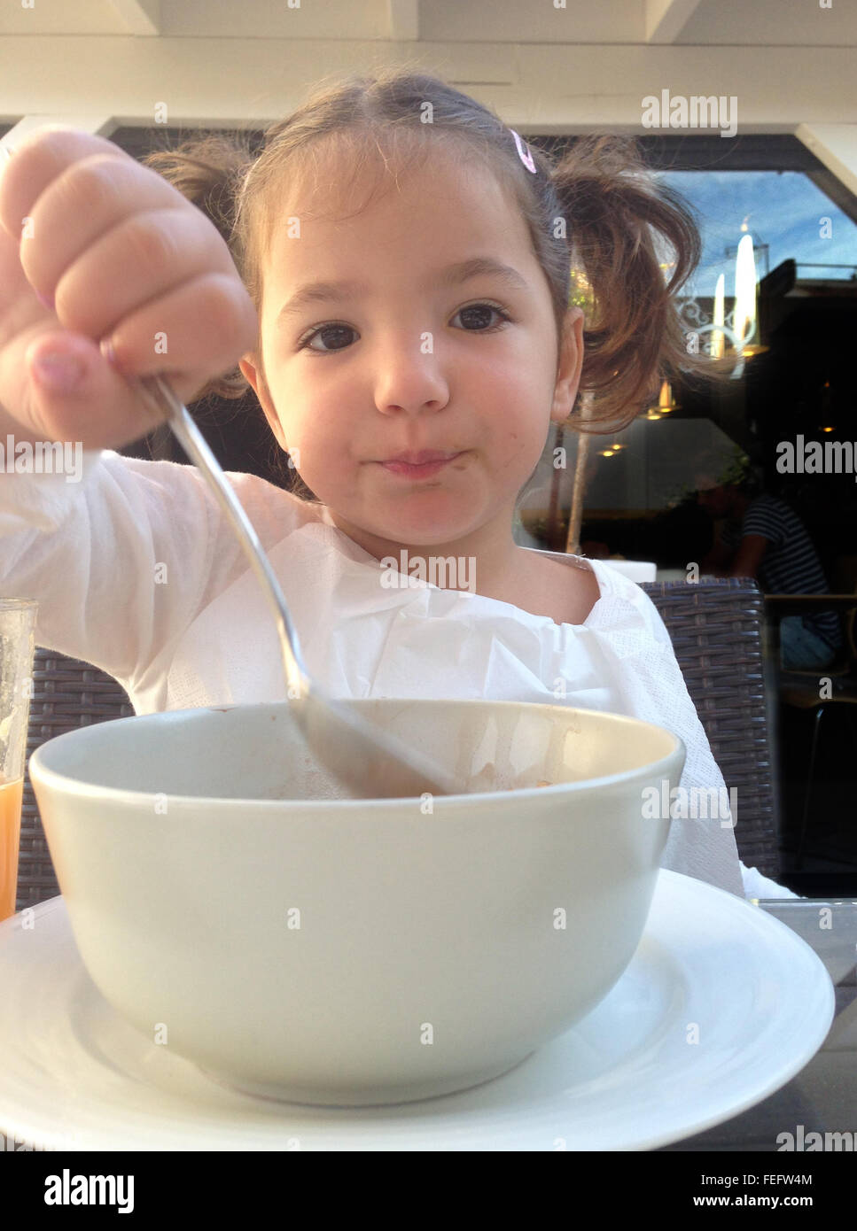 Child girl having a healthy breakfast outdoors. She is eating chocolate ...