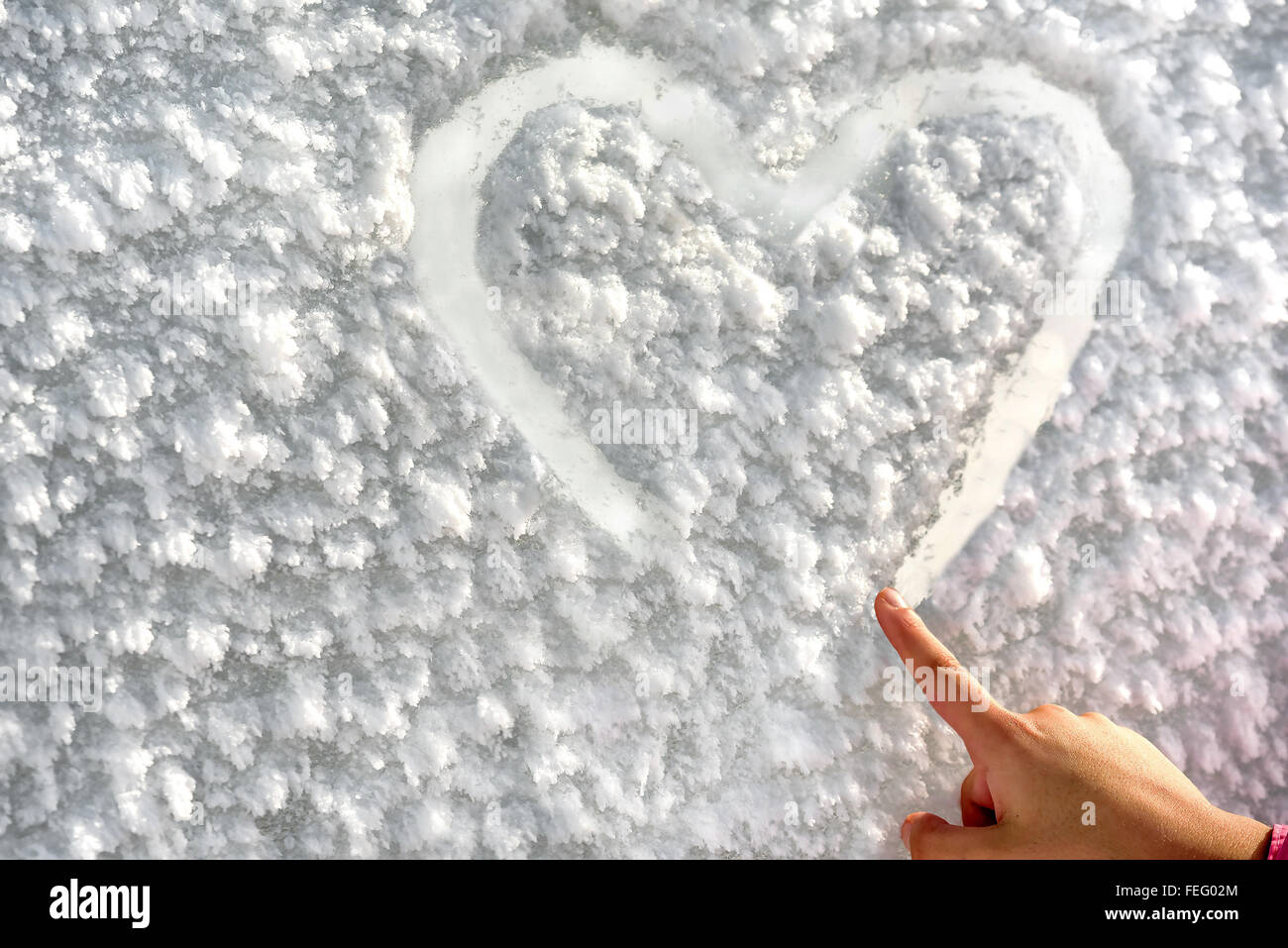 Little girl drawing heart on snow Stock Photo - Alamy