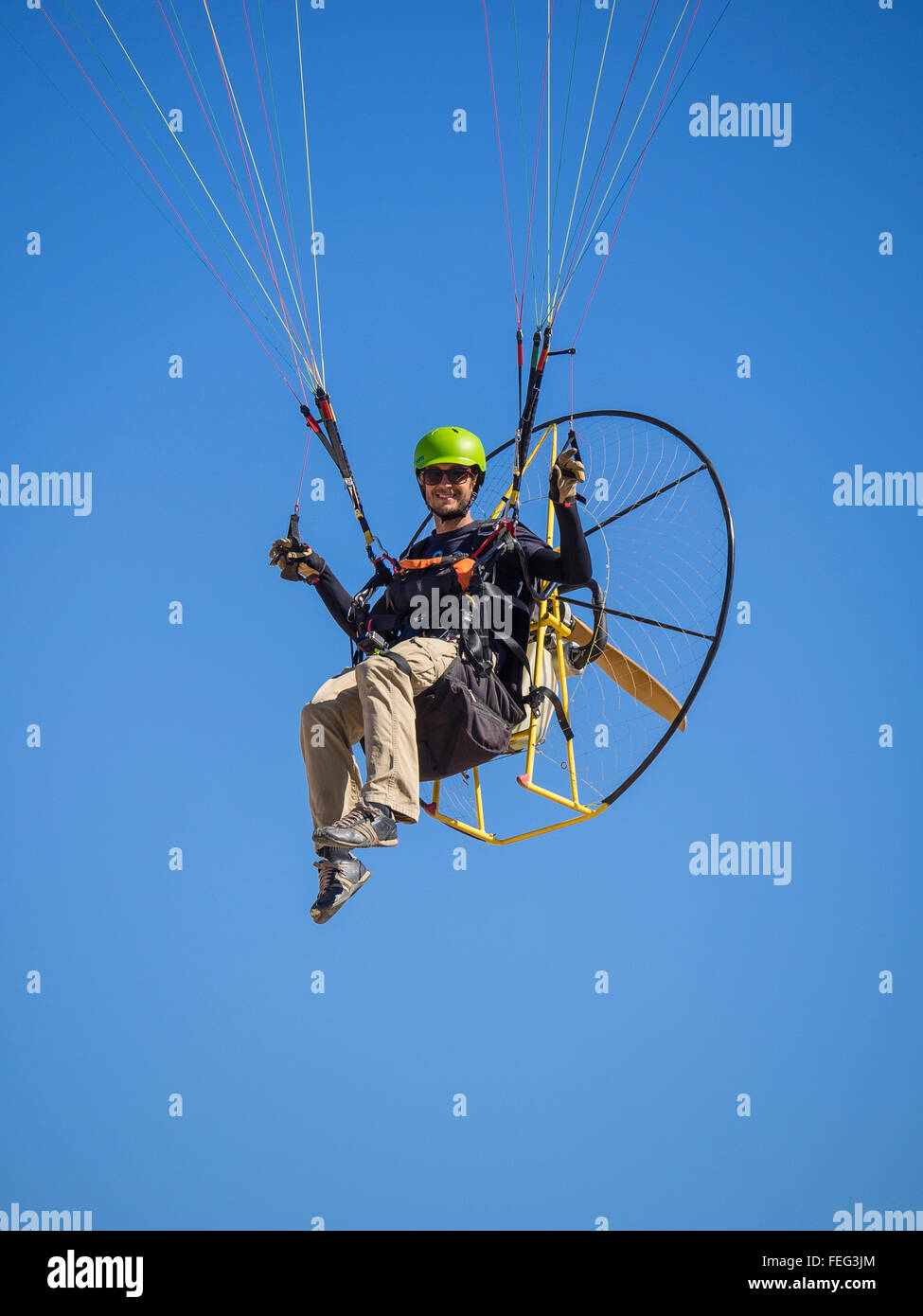 A close-up of a man flies in his paramotor ultralight in the air by the ...