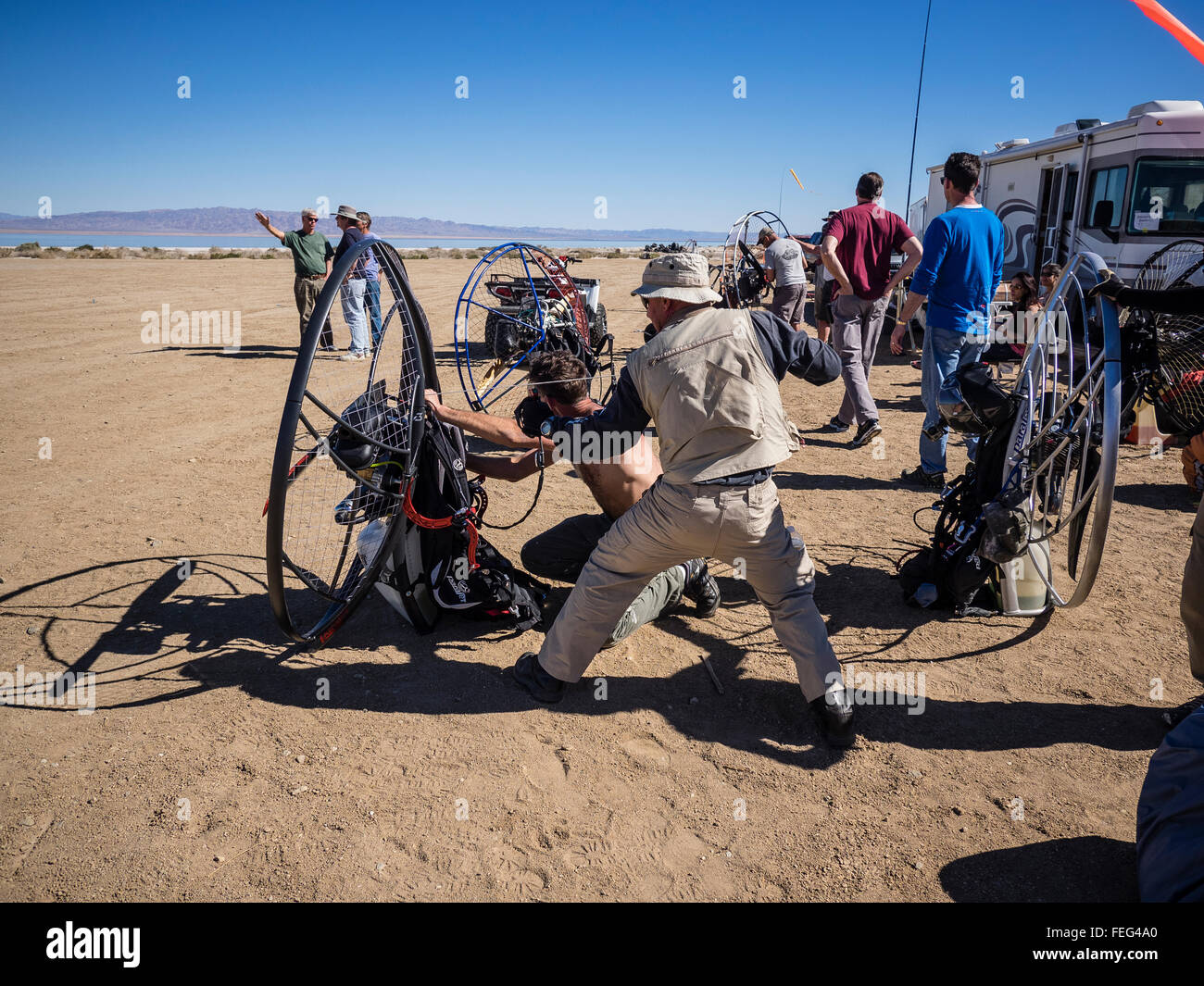 Two male paramotoring pilots work to start the engine of their ...
