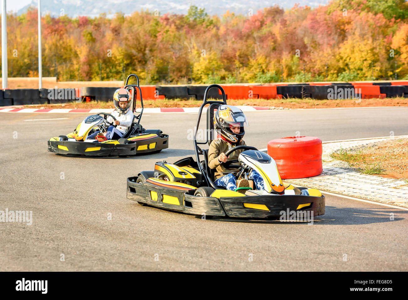 Little girls are driving Go- Kart car in a playground racing track ...