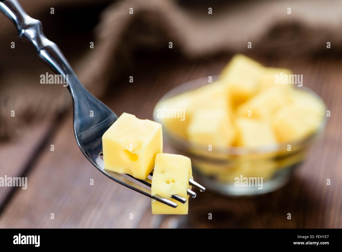 Diced Cheese on a fork (close-up shot) on wooden background Stock Photo ...