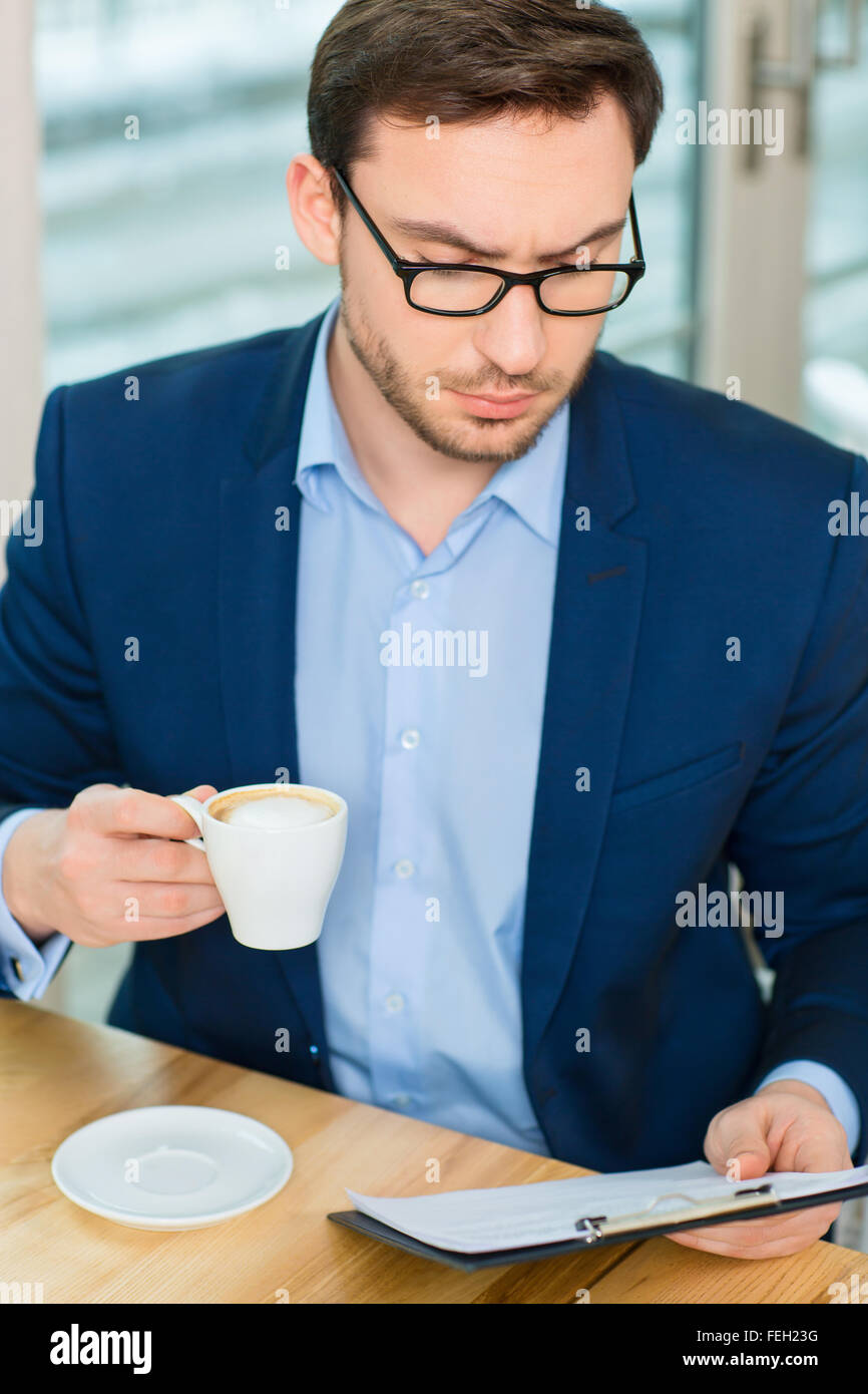 Young good-looking man thoroughly exploring papers Stock Photo - Alamy