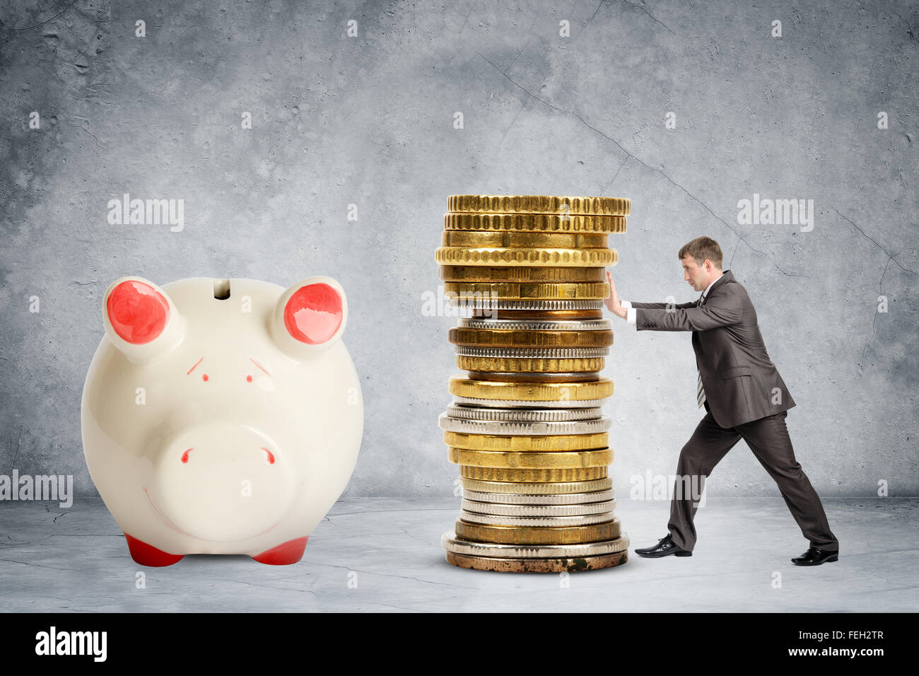 Businessman pushing pile of coins Stock Photo - Alamy
