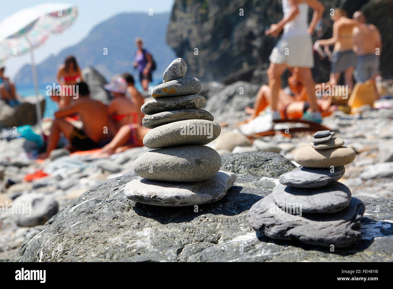 Stacked stones in the beach, with people in the background Stock Photo ...