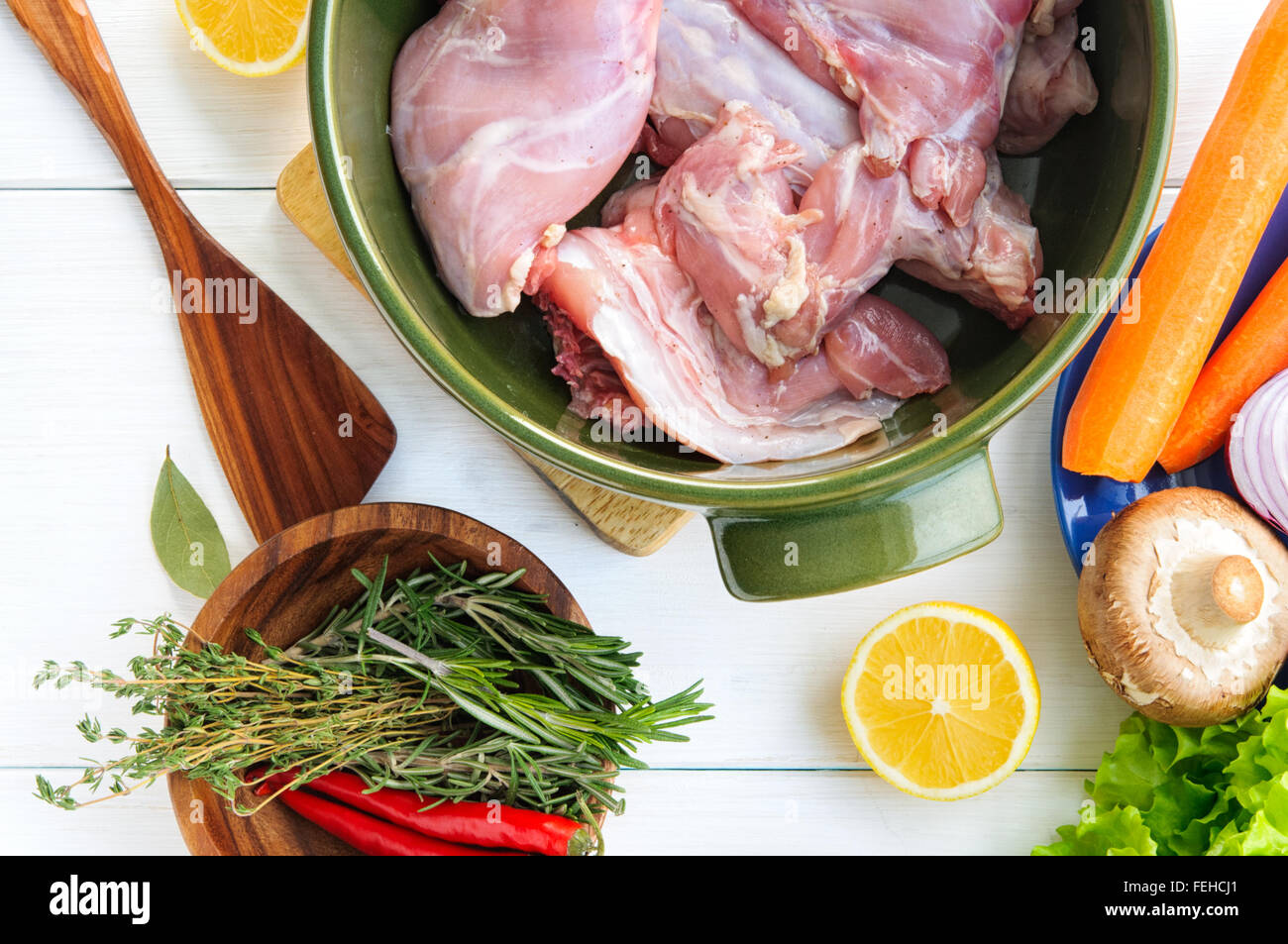 Top flat view of raw rabbit meat with vegetables in round ceramic pot ...