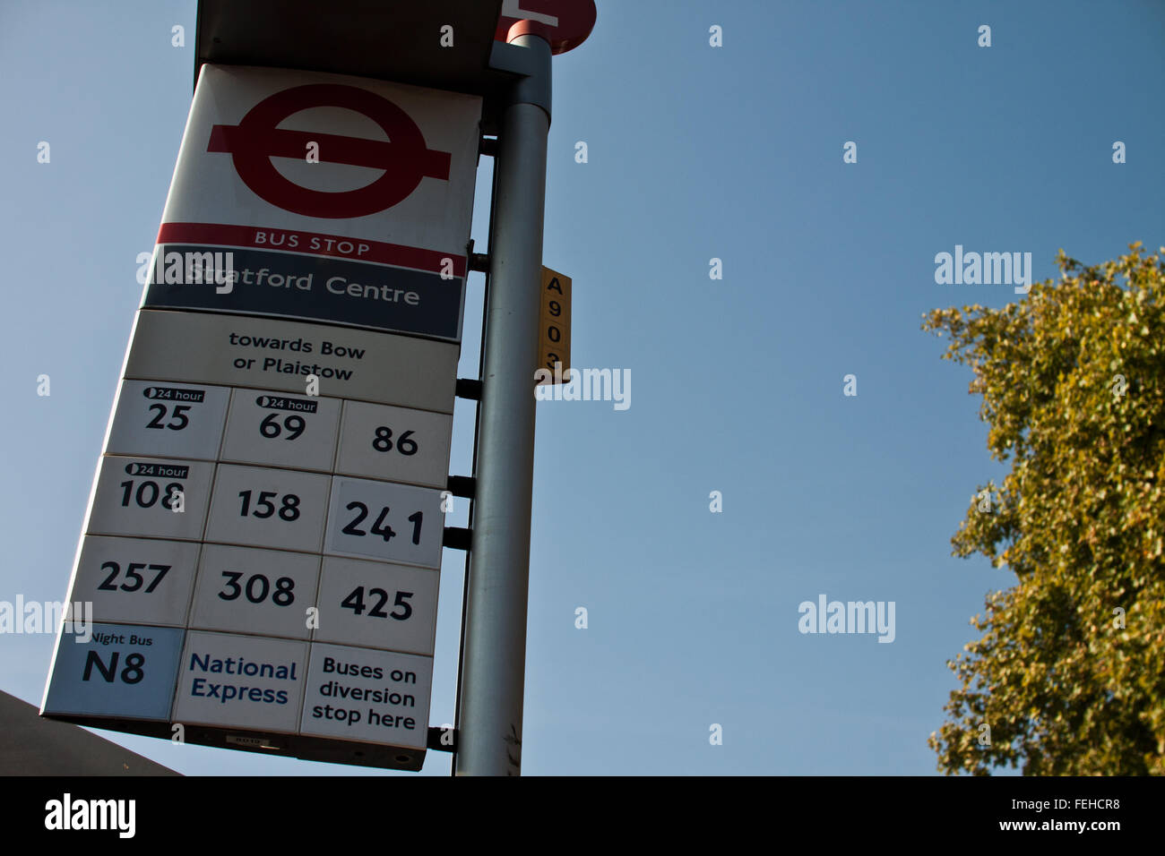 Detail of bus stop in Stratford, East London, with blue sky and trees ...