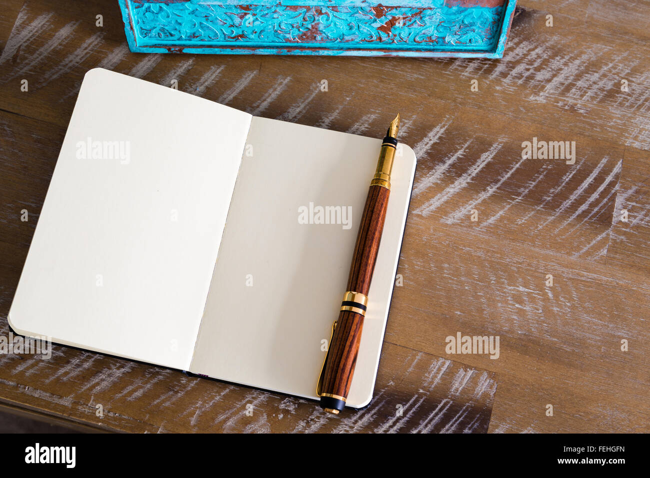 Classic fountain pen and open notebook on wooden table, with turquoise ...