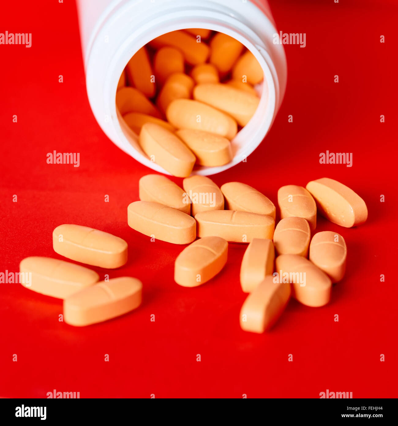 Pills spilling out of pill bottle on red. Top view with copy space ...