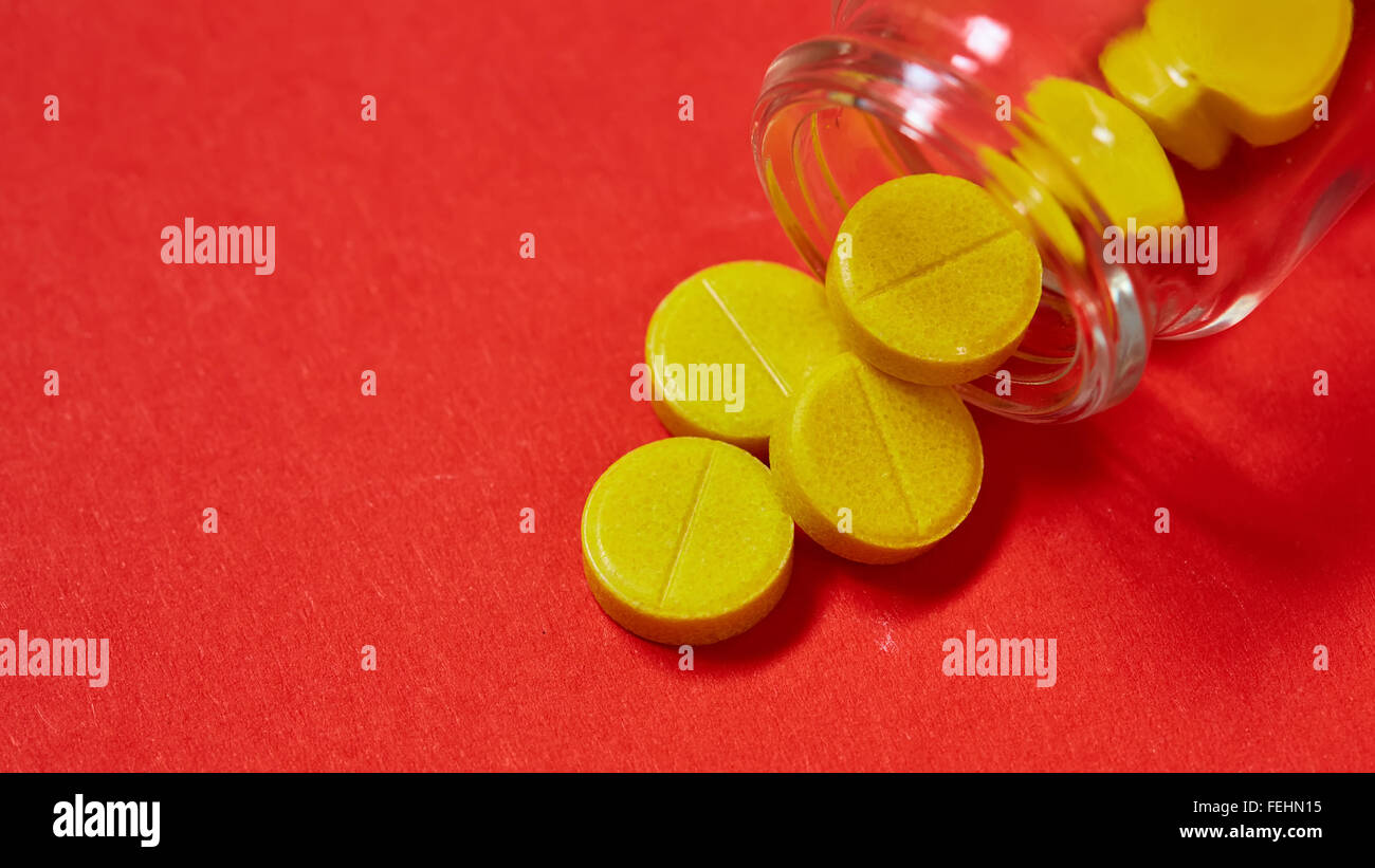 Pills spilling out of pill bottle on red. Top view with copy space ...