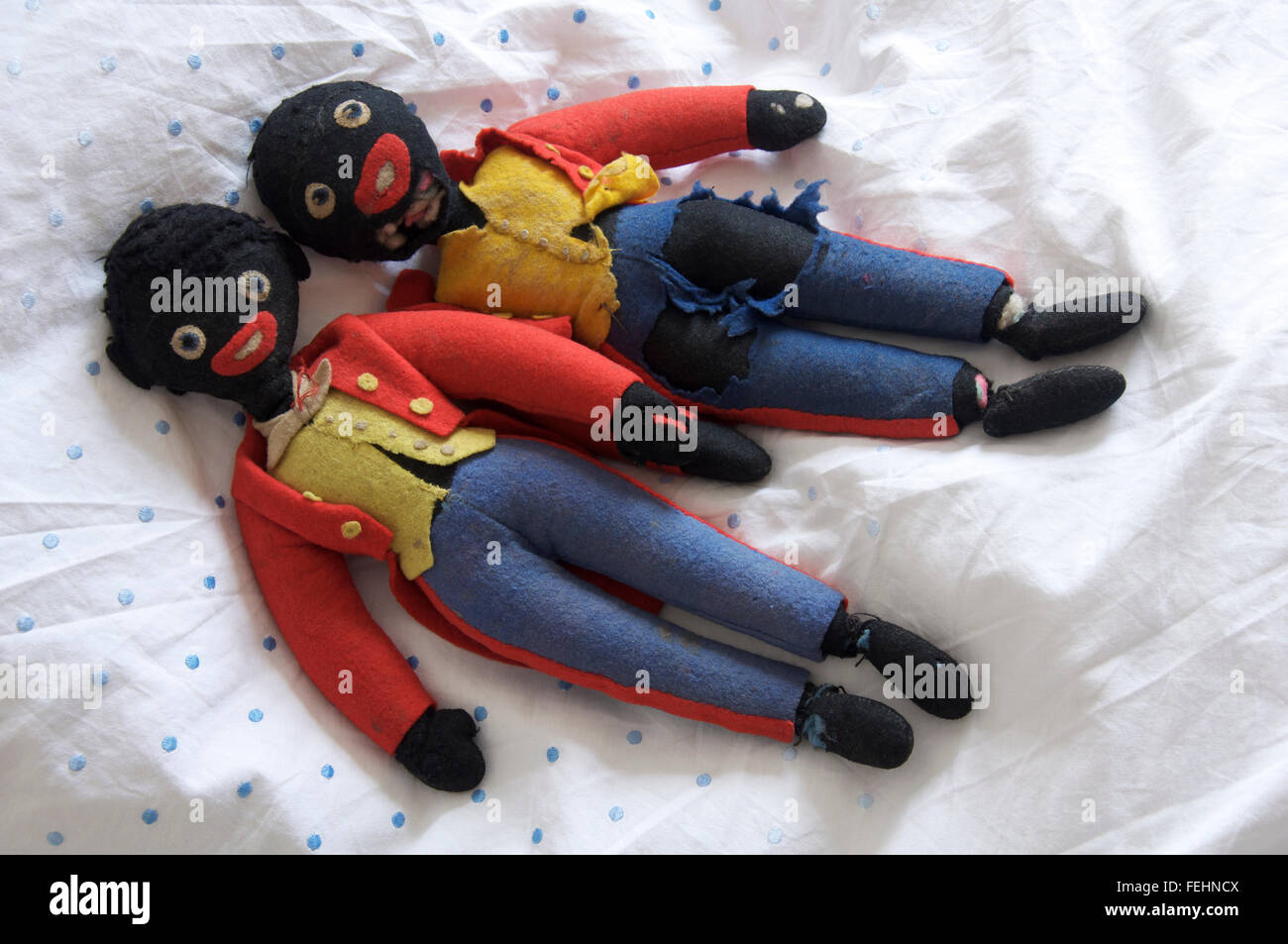 Two old well worn and much loved golliwog dolls lying together on a ...
