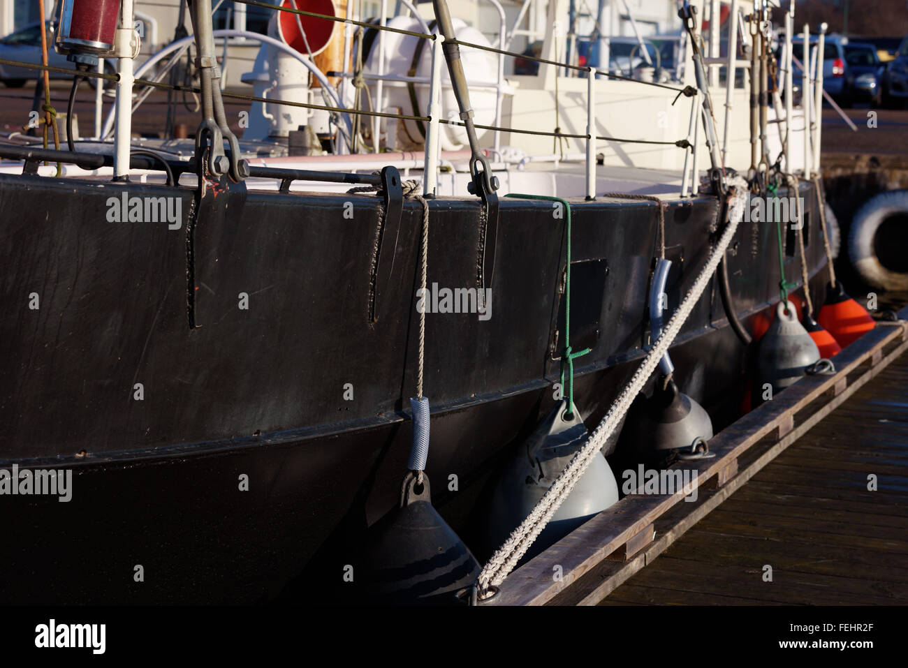 A white rope holds the black sailing ship in place at the docks. Lots ...