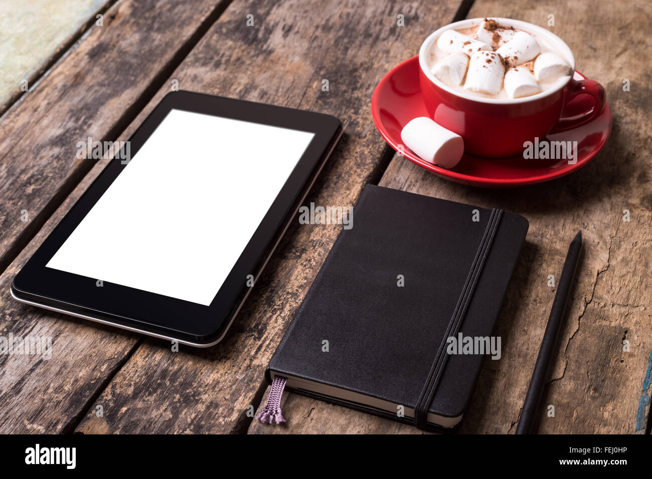 Tablet PC with white screen, black notebook and cup of hot cocoa on ...