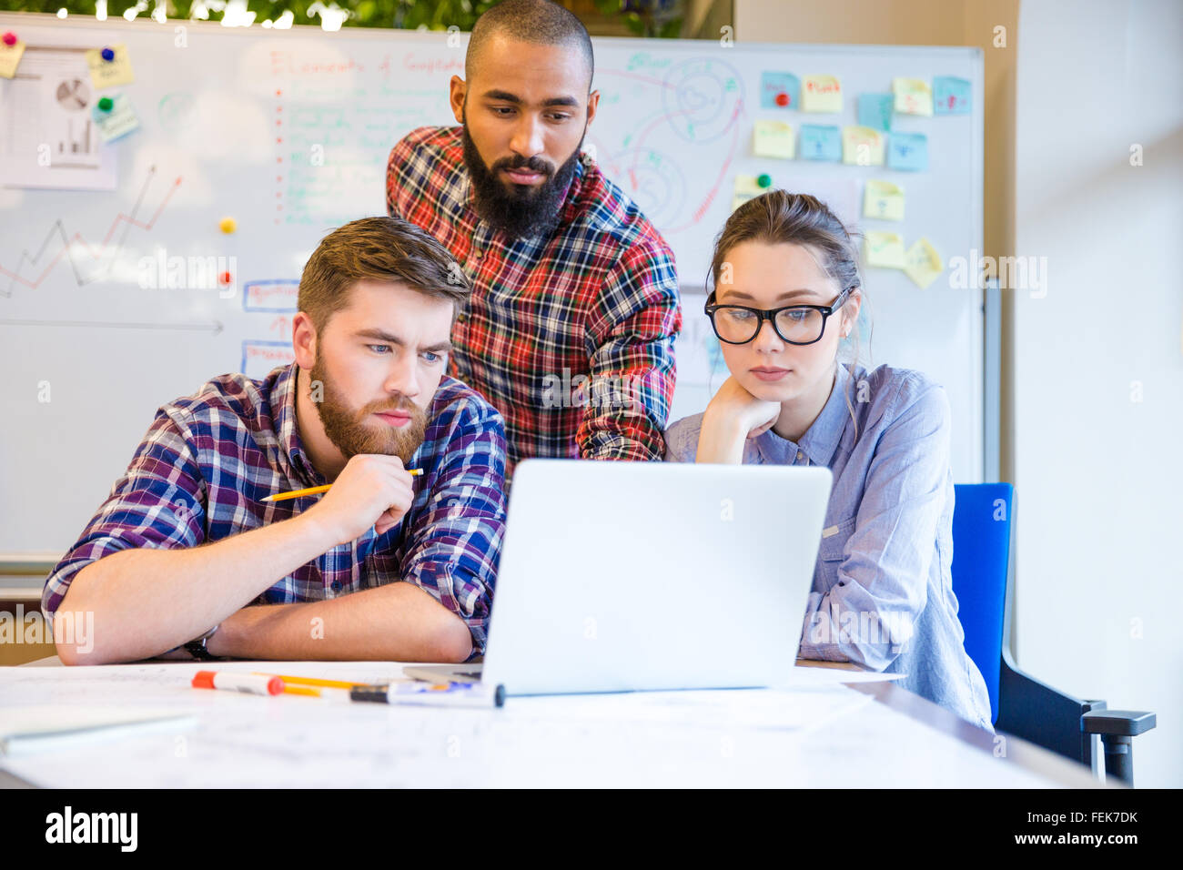 Focused serious multiethnic group of young people sitting and working ...