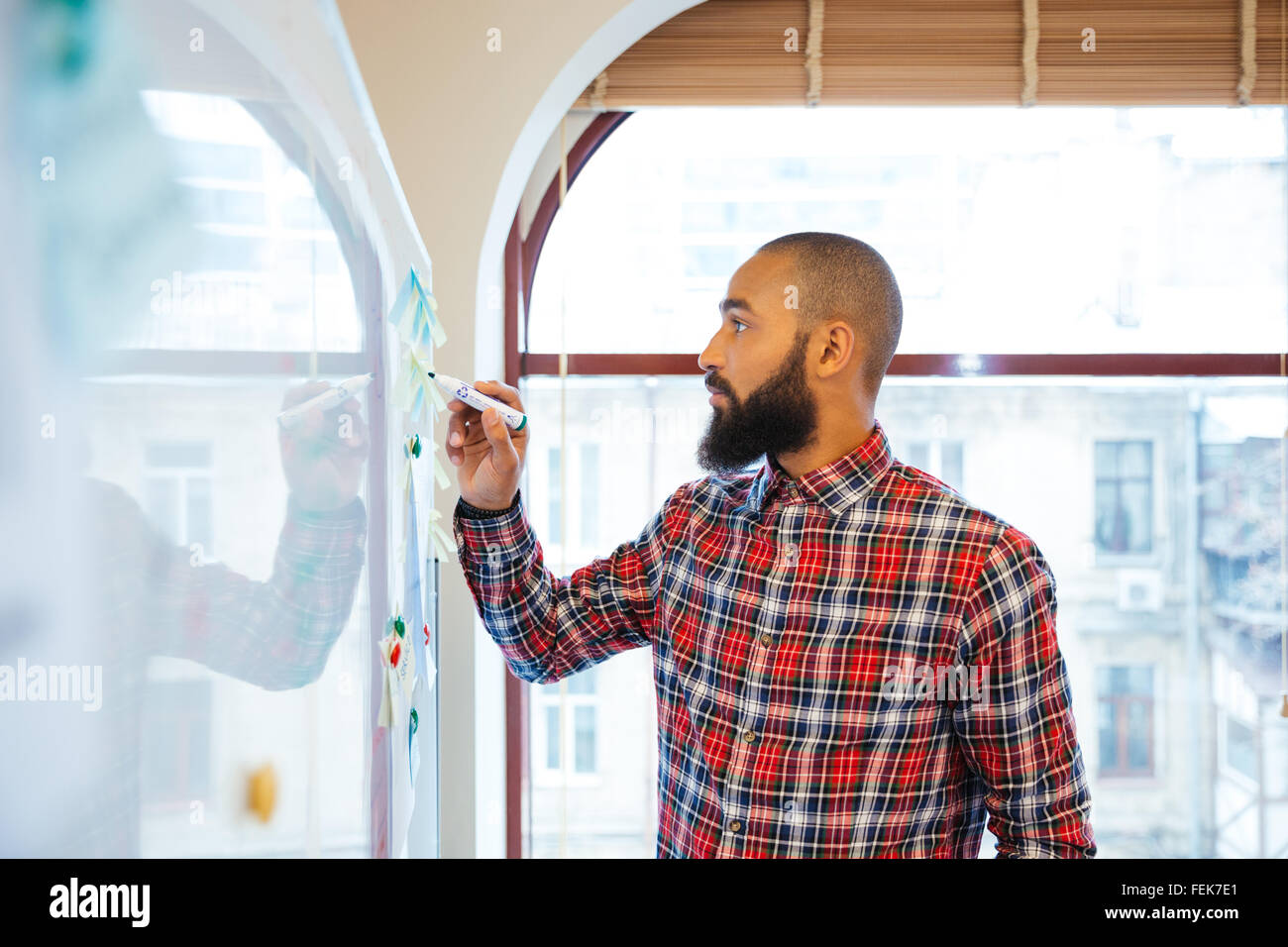 Profile of handsome african man with beard standing and writing on ...