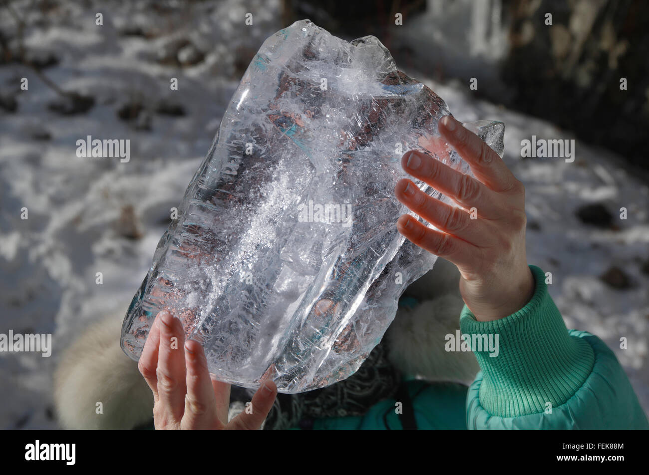 woman's hands holding a large piece of ice from the frozen mountain ...