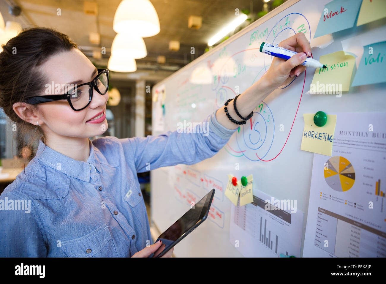 Happy businesswoman writing something on whiteboard in office Stock ...