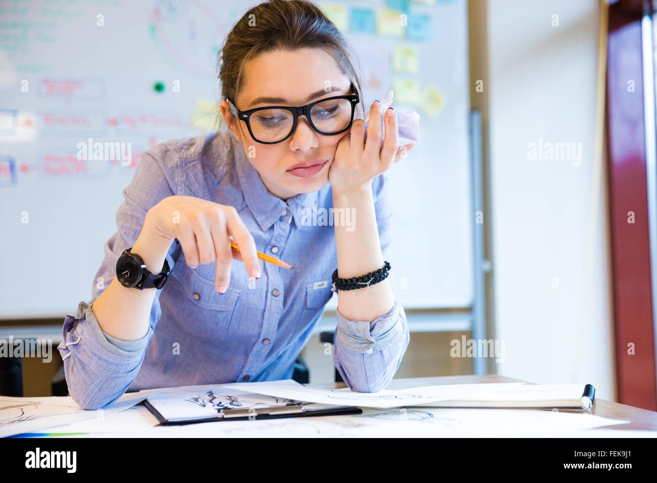 Bored pretty young woman fashion designer in glasses working and making ...