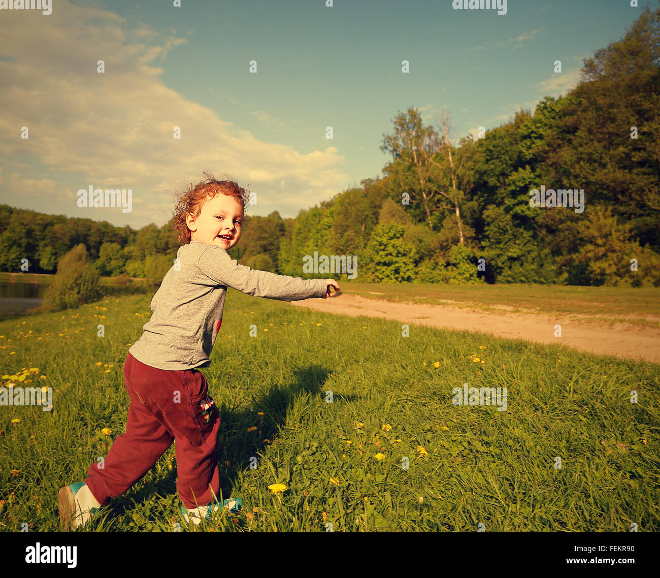Happy smiling kid girl running on green grass outdoors summer ...