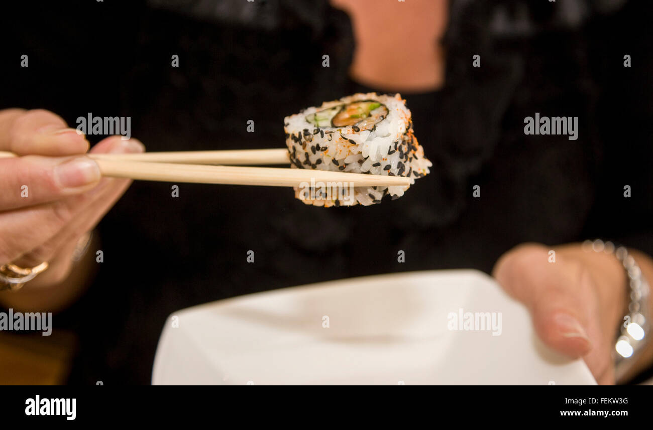 Lady eating sushi with chopsticks Stock Photo - Alamy