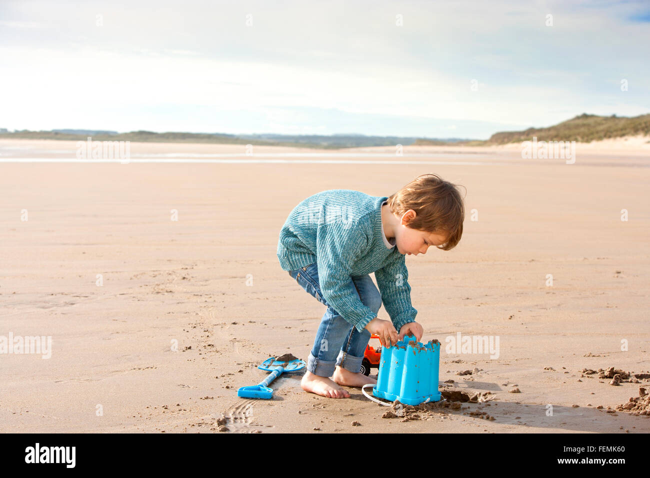 Little boy digging on the beach with a bucket Stock Photo - Alamy