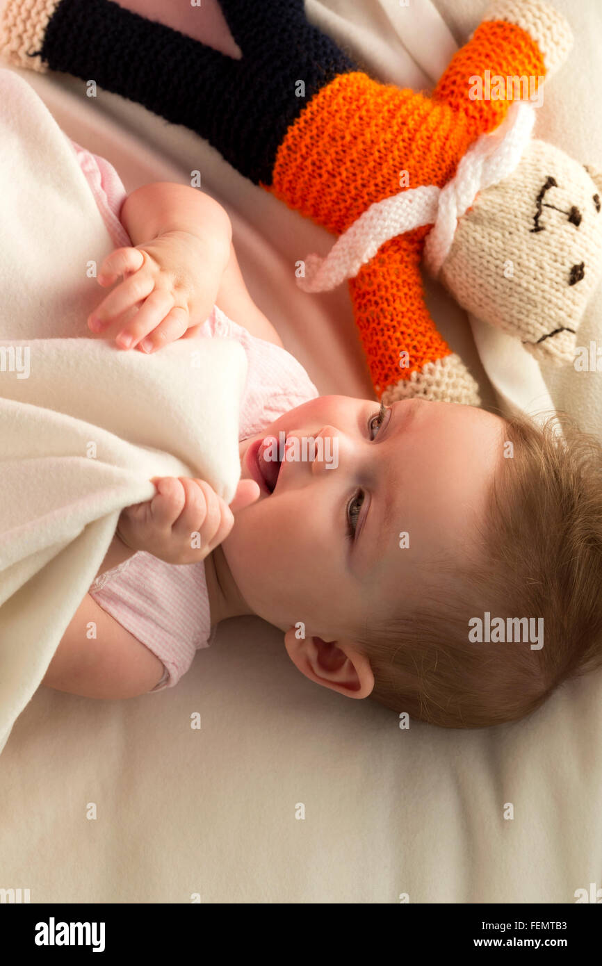 Baby lying awake in her cot holding a teddy Stock Photo - Alamy