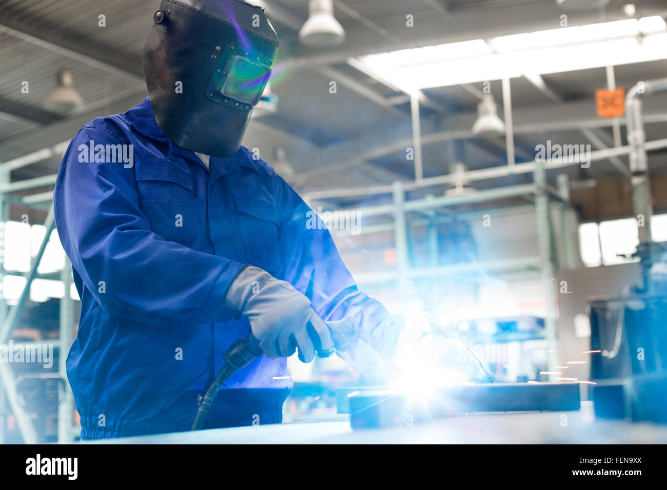 Welder in protective workwear using welding torch in steel factory ...