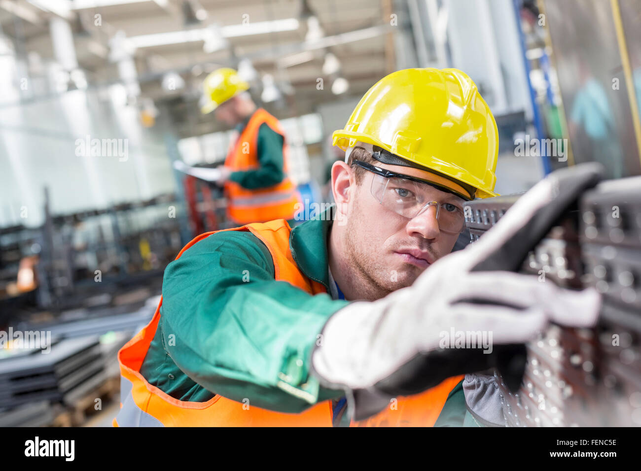 Focused worker examining steel part in factory Stock Photo - Alamy