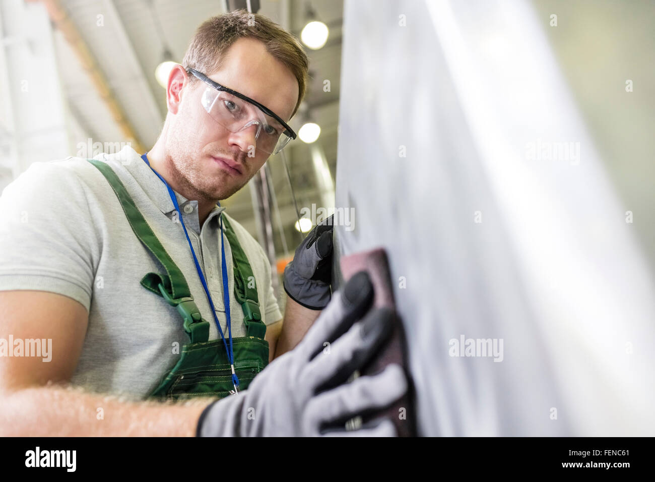 Focused worker sanding part in factory Stock Photo - Alamy