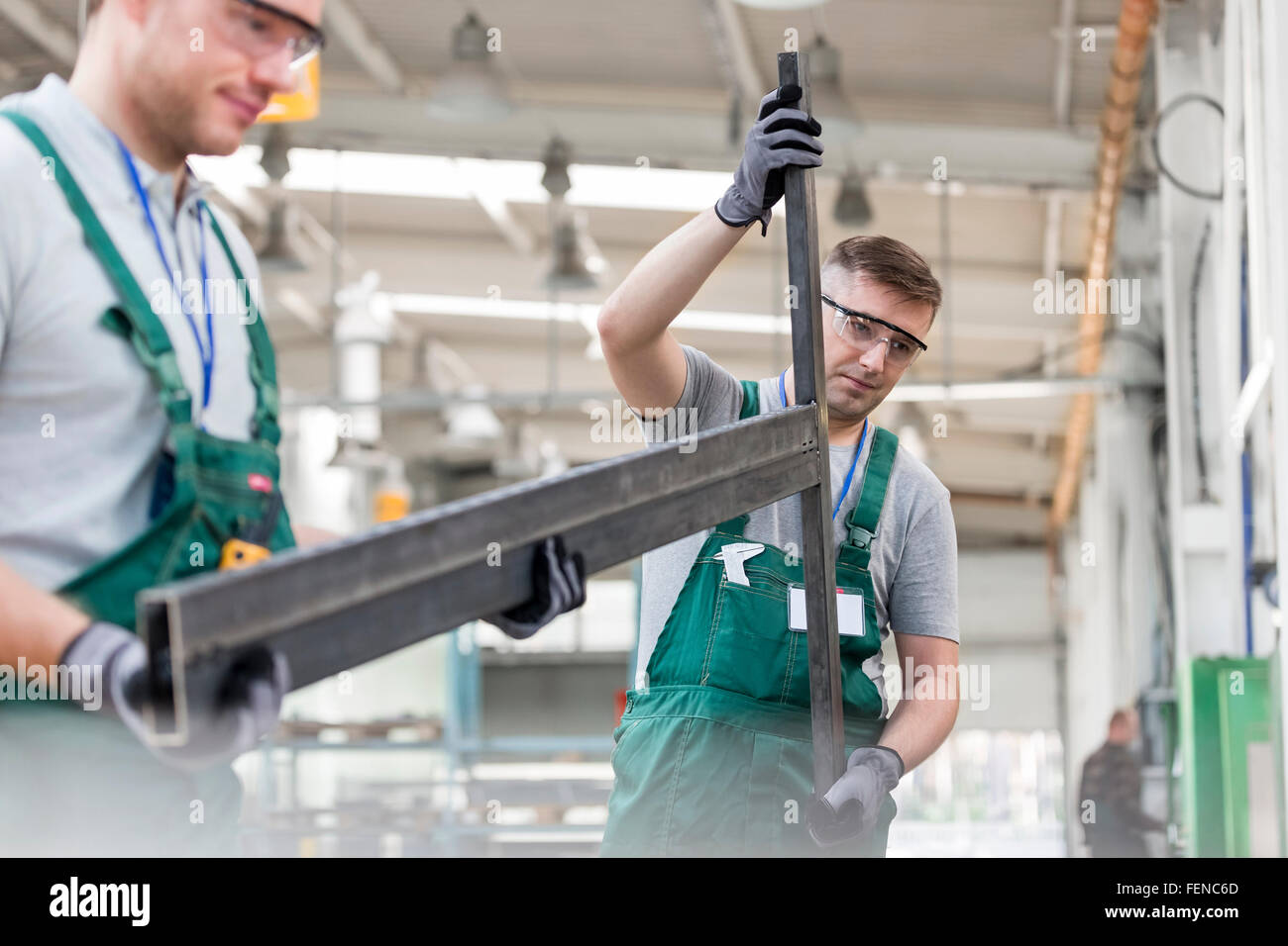 Workers carrying part in factory Stock Photo - Alamy