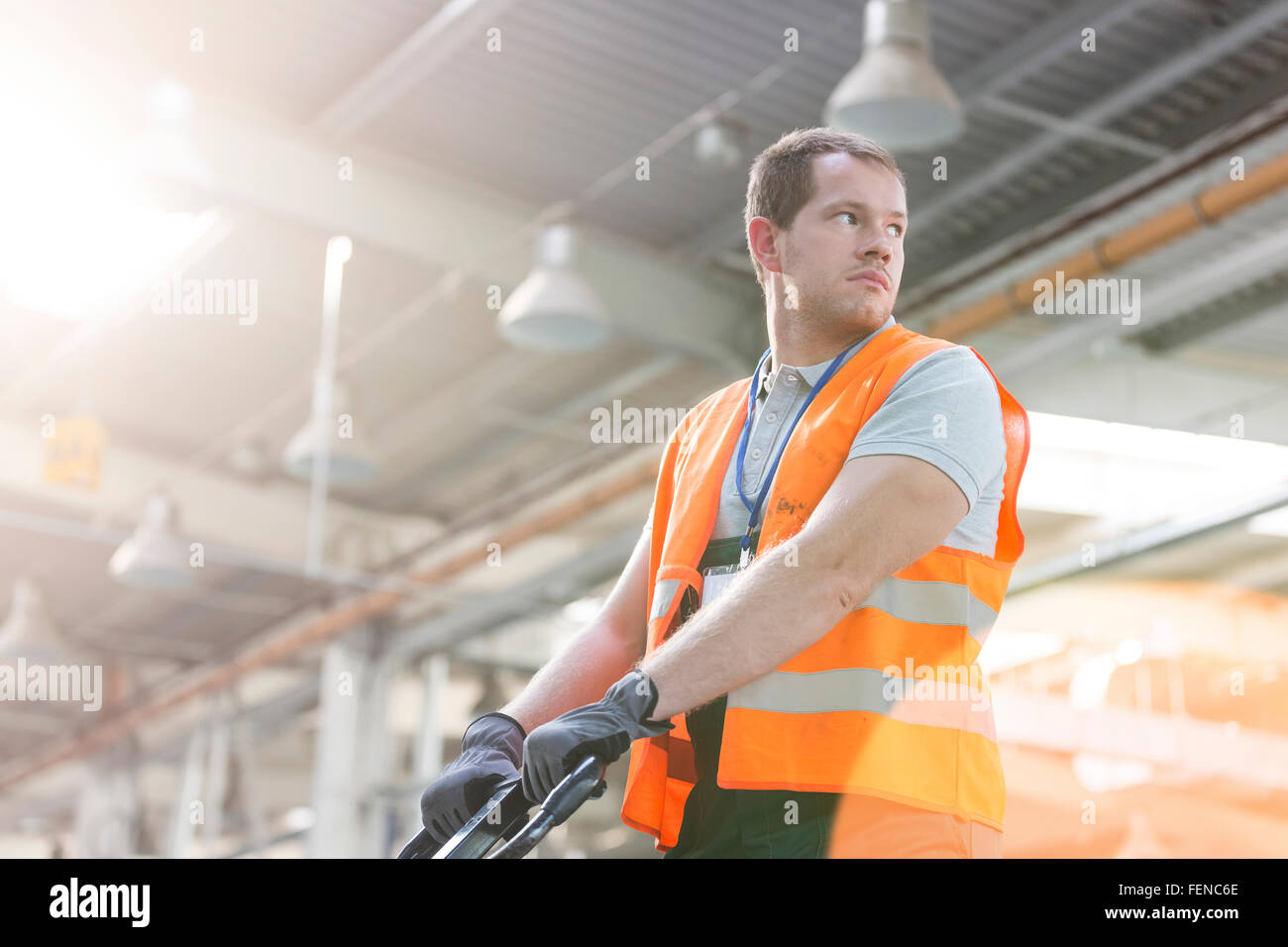Worker in protective workwear pulling pallet truck in factory Stock ...